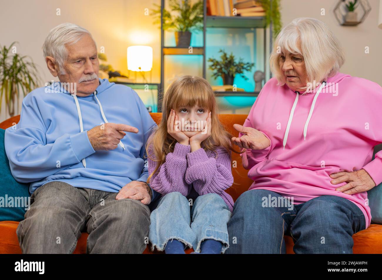 Irritated grandfather and grandmother scolding granddaughter for bad ...