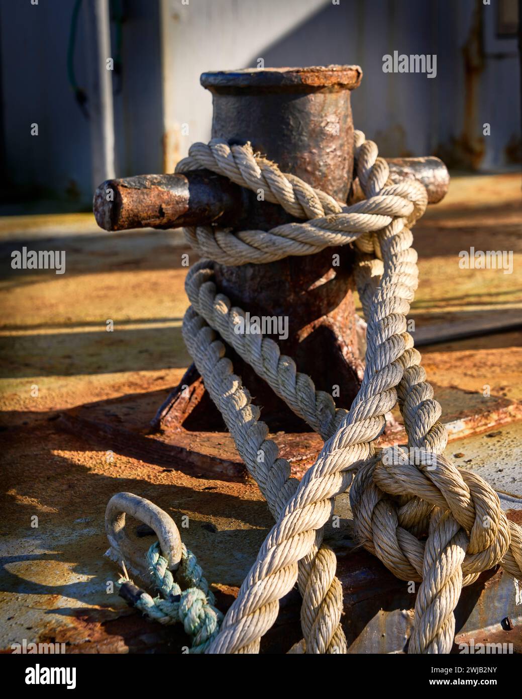 Closeup of a tie up line on a boat and the rusty cleat that it is tied ...