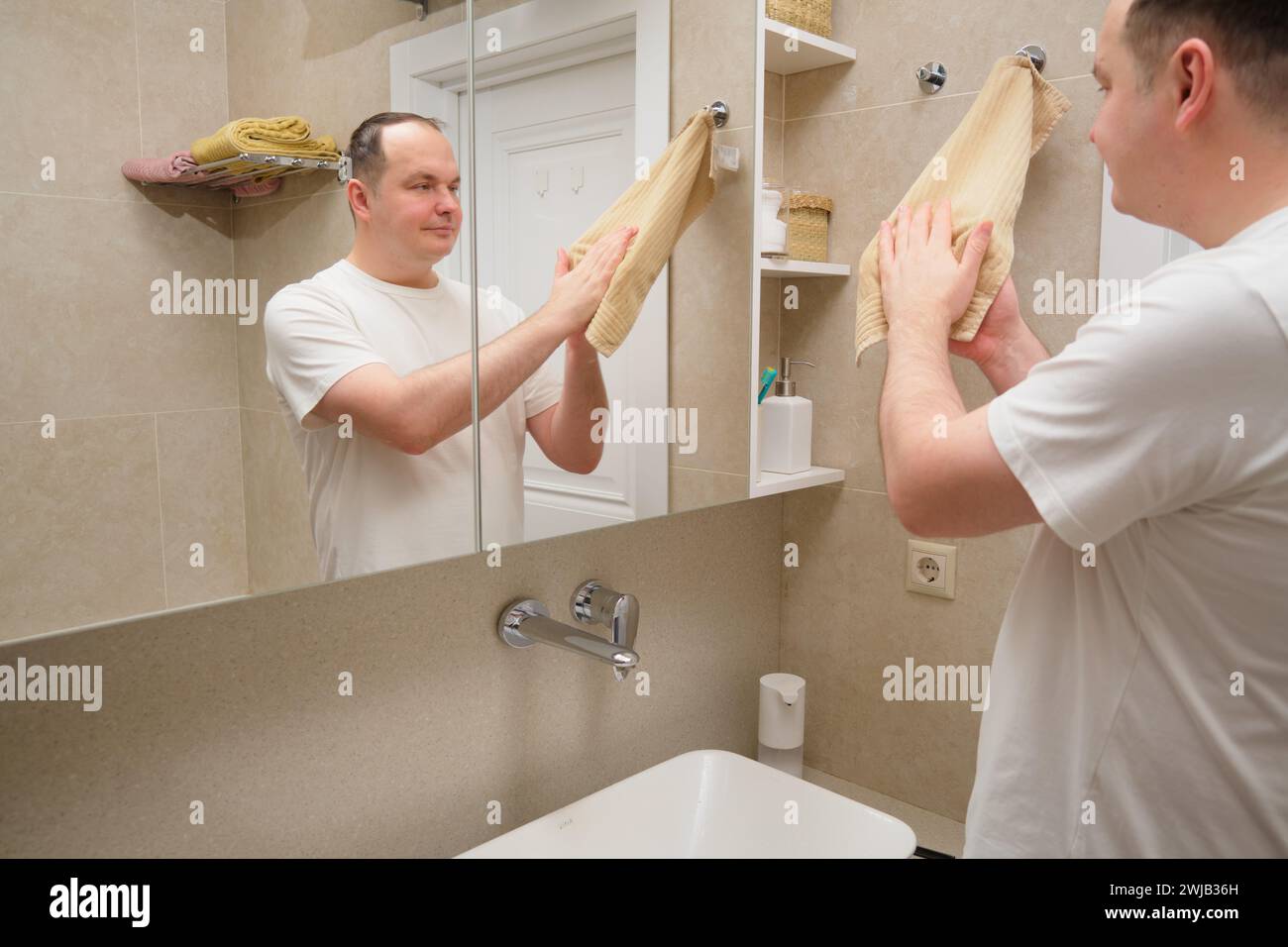 A man wipes his hand with a towel after washing in the bathroom in ...