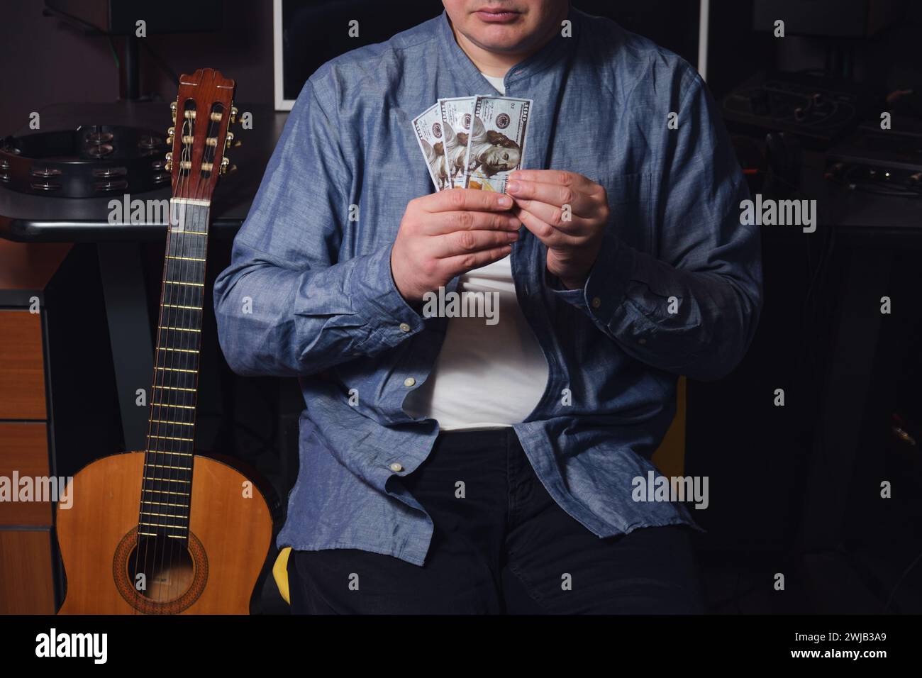A musician in a recording studio holds dollar money in his hands. The ...