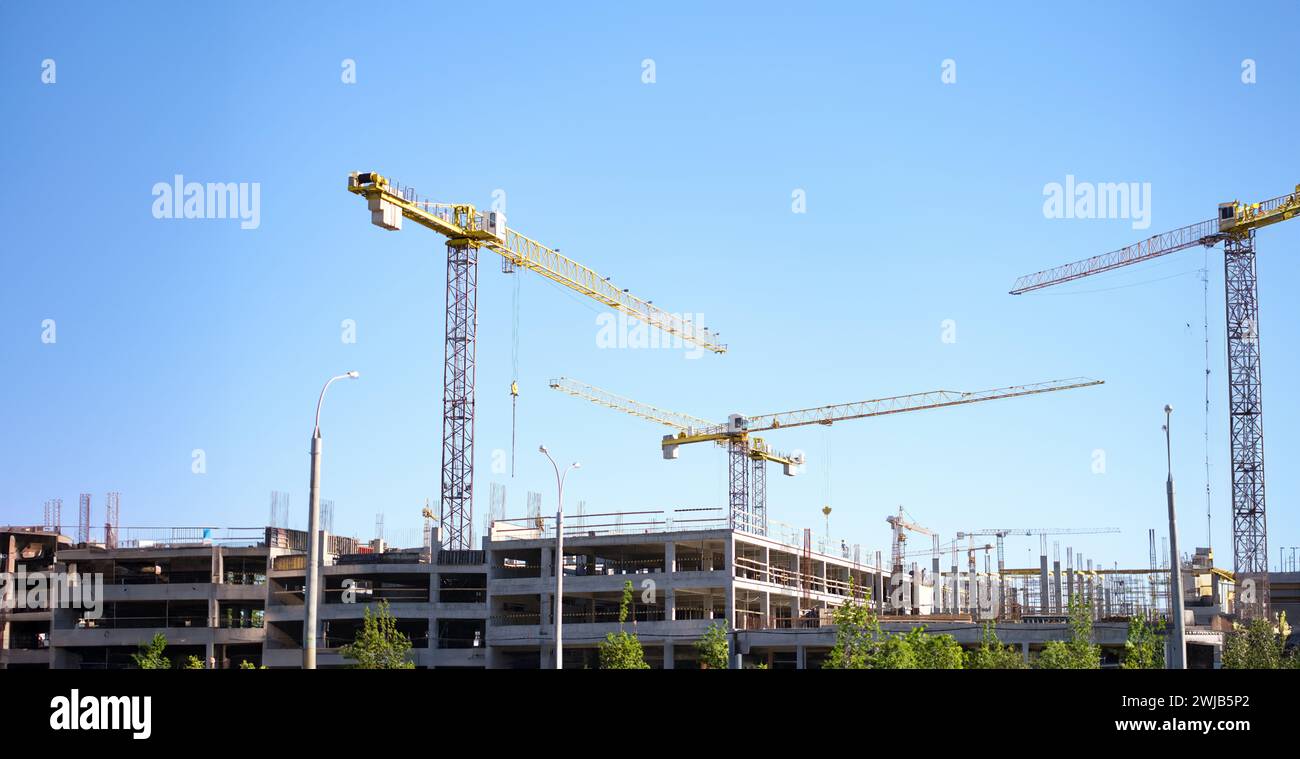 Many construction cranes standing near multi-storey buildings at site ...