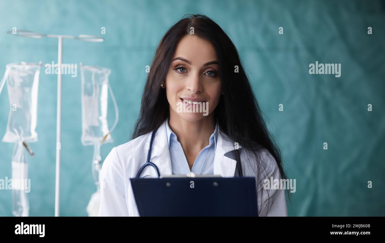 Beautiful woman doctor stand with folder smiling Stock Photo - Alamy