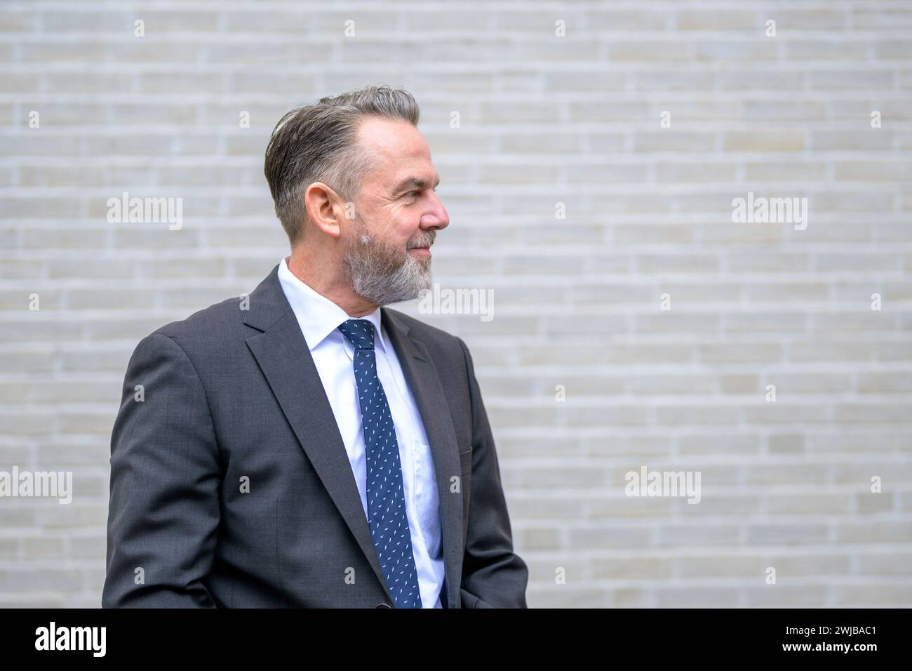 Side view of a sixty year old gray man in front of a white brick wall ...