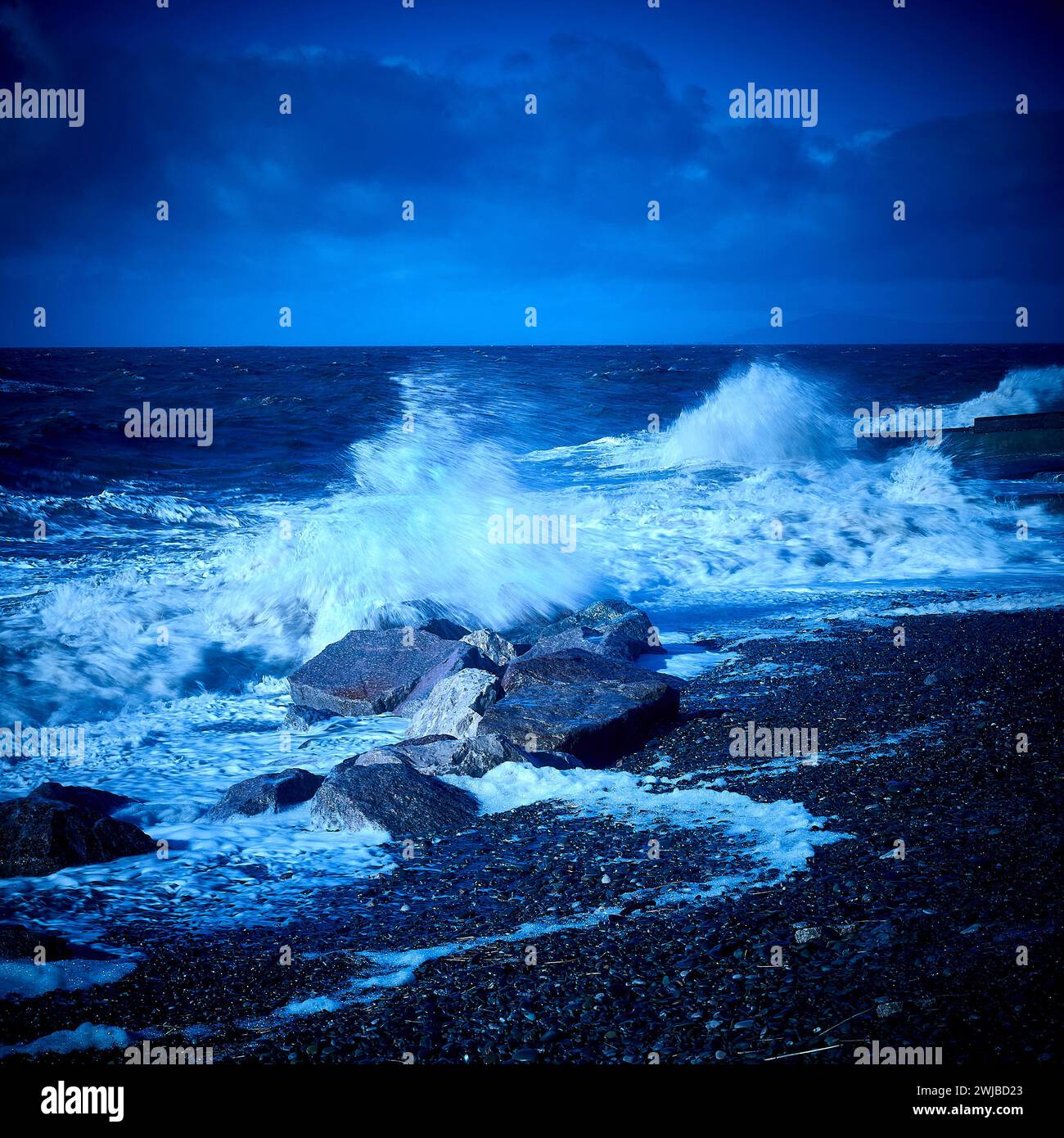Waves breaking onto rocks under moonlight Stock Photo - Alamy