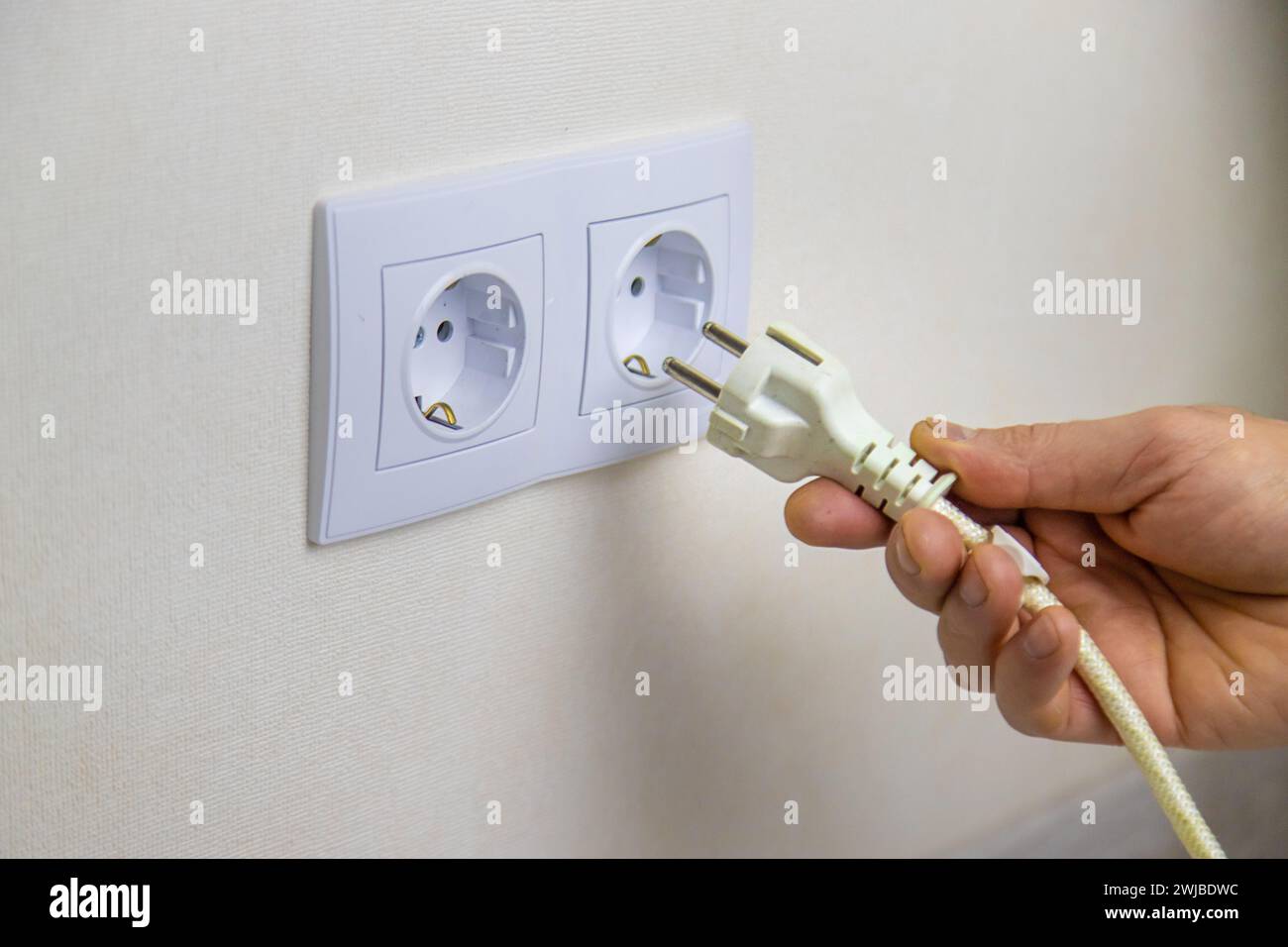 Hand plugs power cord wall hi-res stock photography and images - Alamy