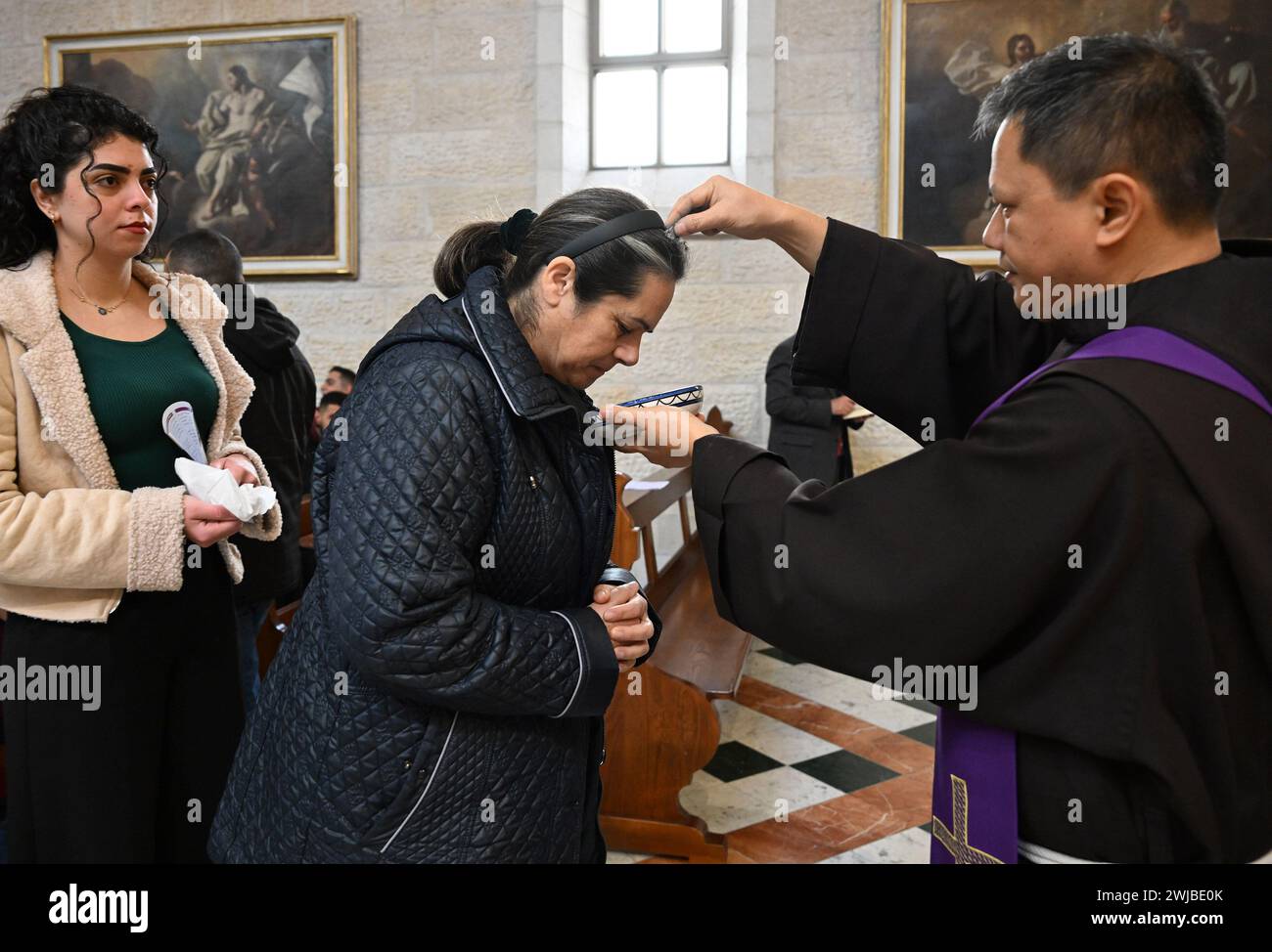 Bethlehem, West Bank. 14th Feb, 2024. A Palestinian Catholic receive ...