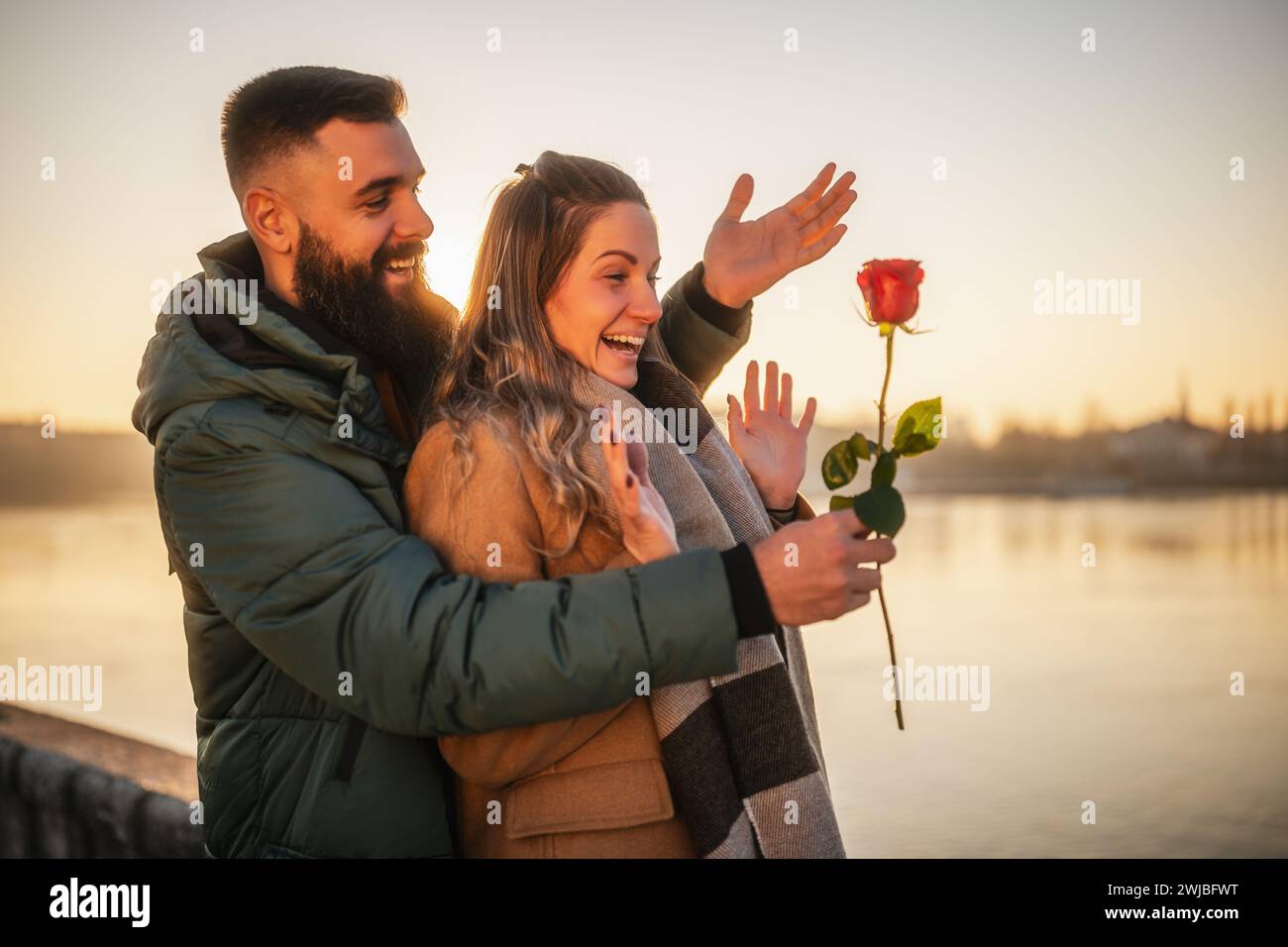 Happy man giving red rose to his woman while they enjoy spending time ...