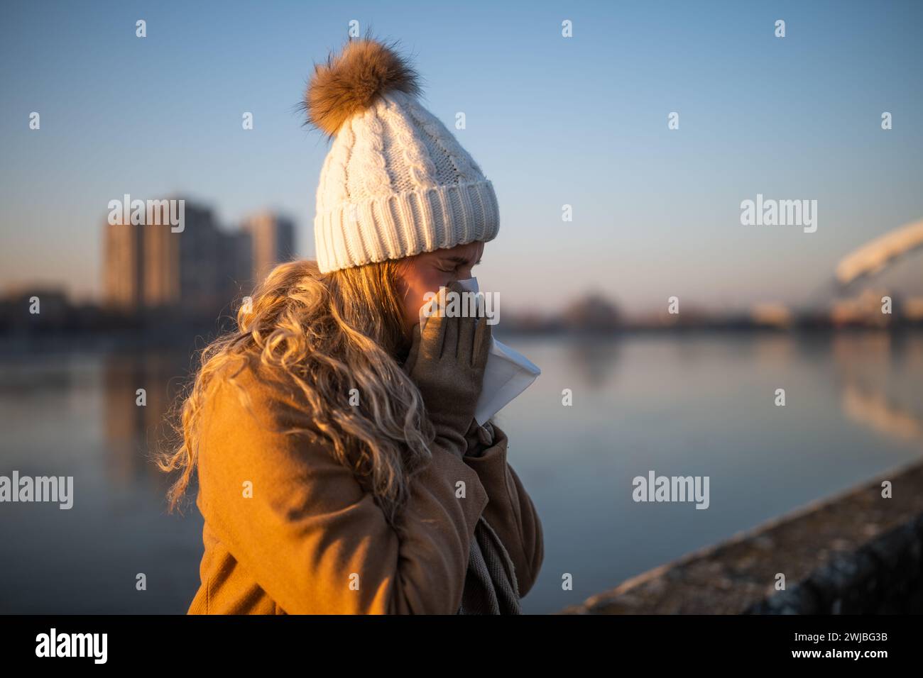 Woman in warm clothing blowing nose outdoor Stock Photo - Alamy