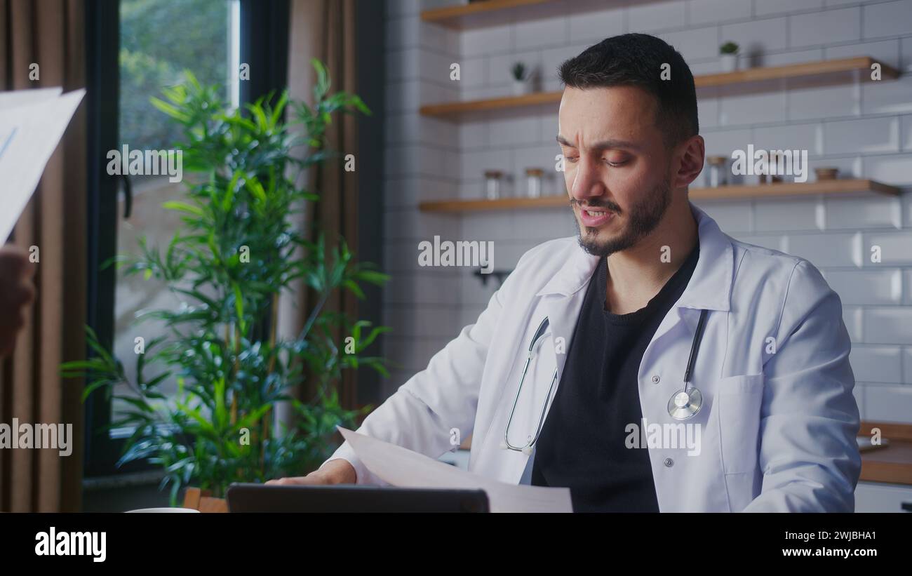 Experienced doctor wearing white coat taking patient reports from his ...