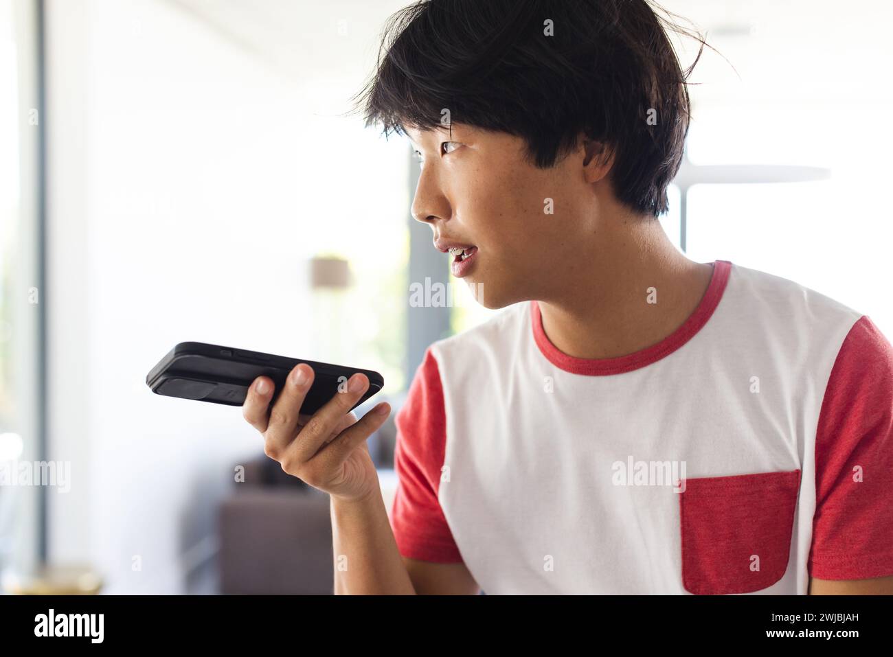 Teenage Asian boy speaks into a phone at home, with copy space Stock ...