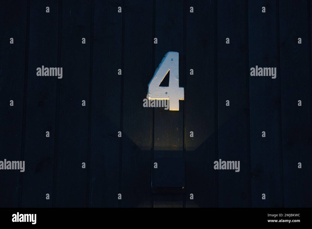 The number 4 mounted on a wooden plank wall with lighting from an ...