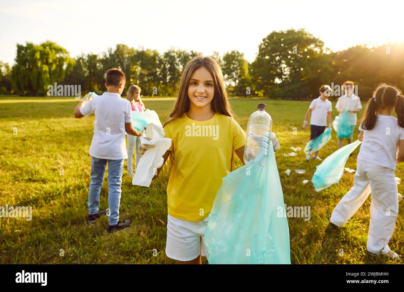 Child girl and children volunteers cleaning trash from the grass in the ...