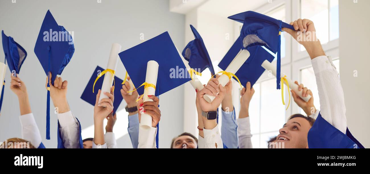 Graduates students with hands up holding diplomas and graduation cap ...