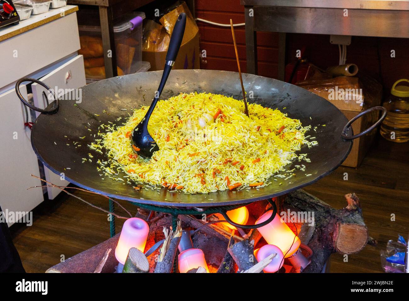 Cook prepares pilaf, a dish of rice and meat on a campfire in the ...