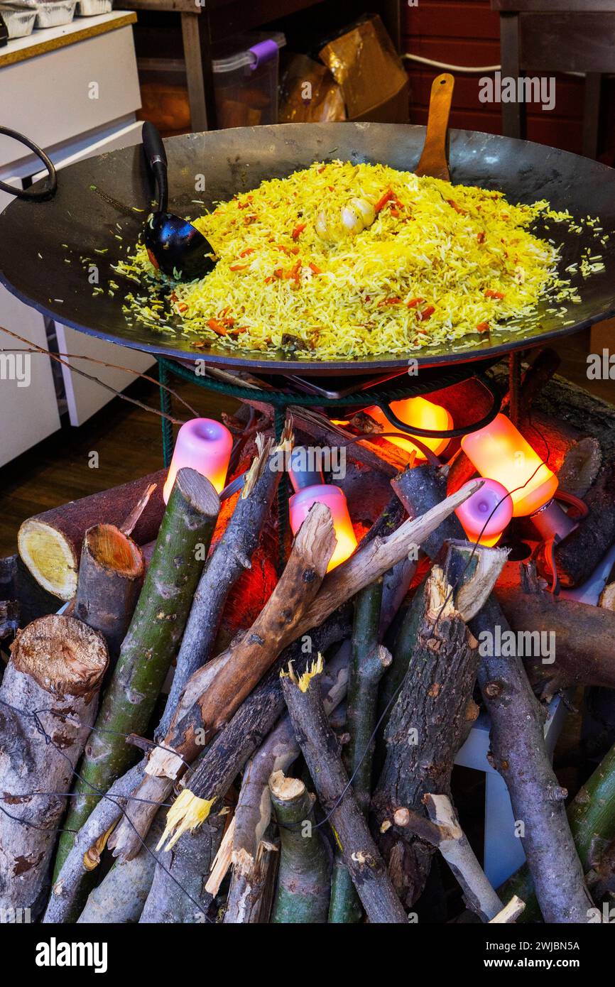 Cook prepares pilaf, a dish of rice and meat on a campfire in the ...
