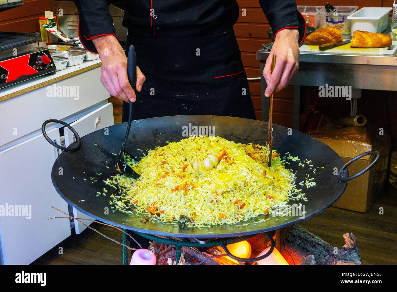 Cook prepares pilaf, a dish of rice and meat on a campfire in the ...