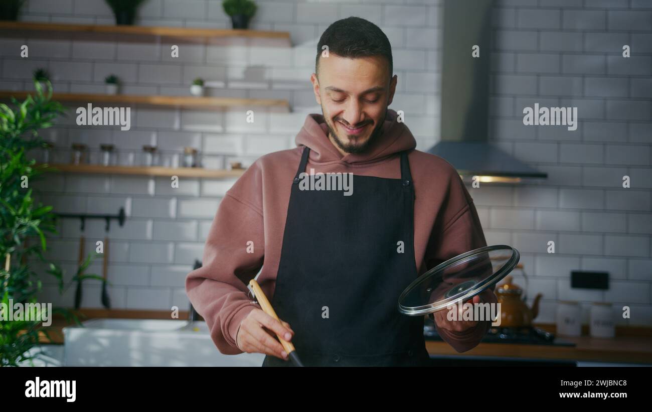 Man stirring soup with spoon and tasting. Happy male enjoying food ...