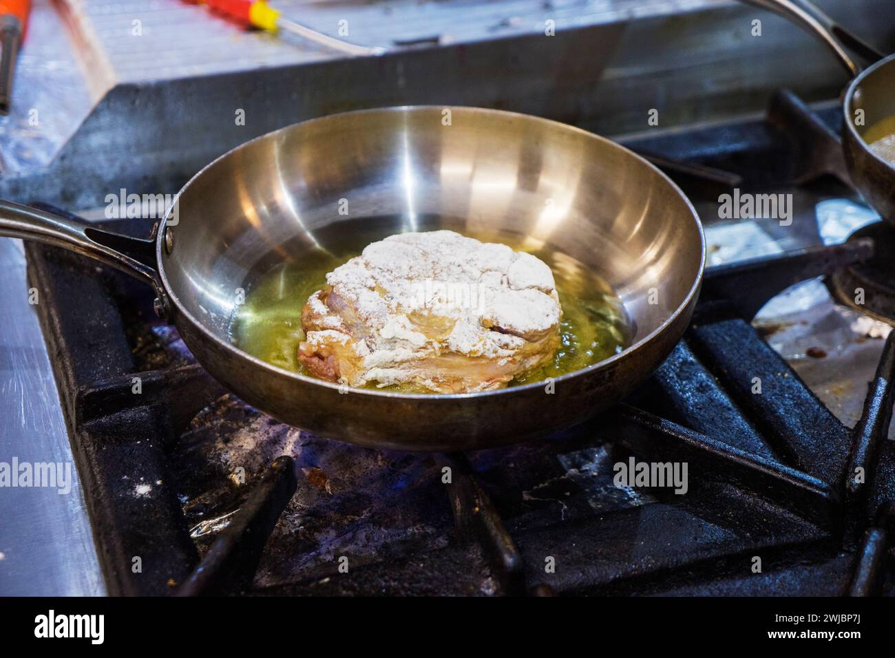 A piece of lamb leg is fried in oil in an iron pan Stock Photo - Alamy