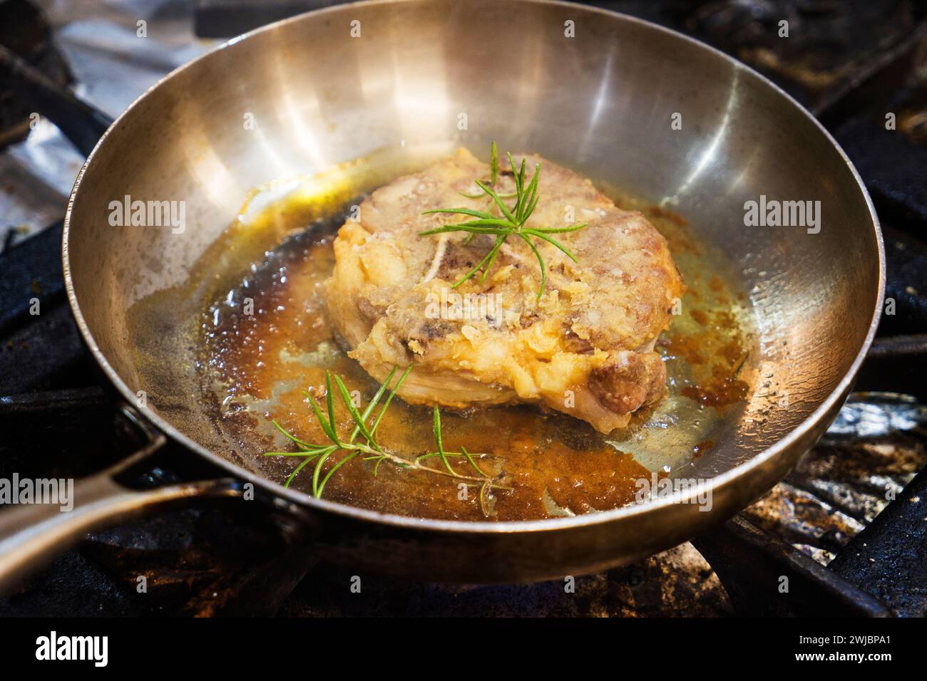 A piece of lamb leg is fried in oil in an iron pan Stock Photo - Alamy