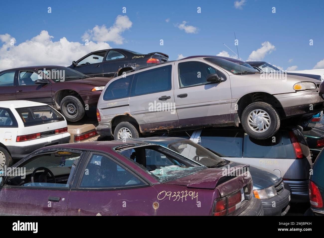 Stacked automobiles and mini van at scrap metal recycling junkyard ...