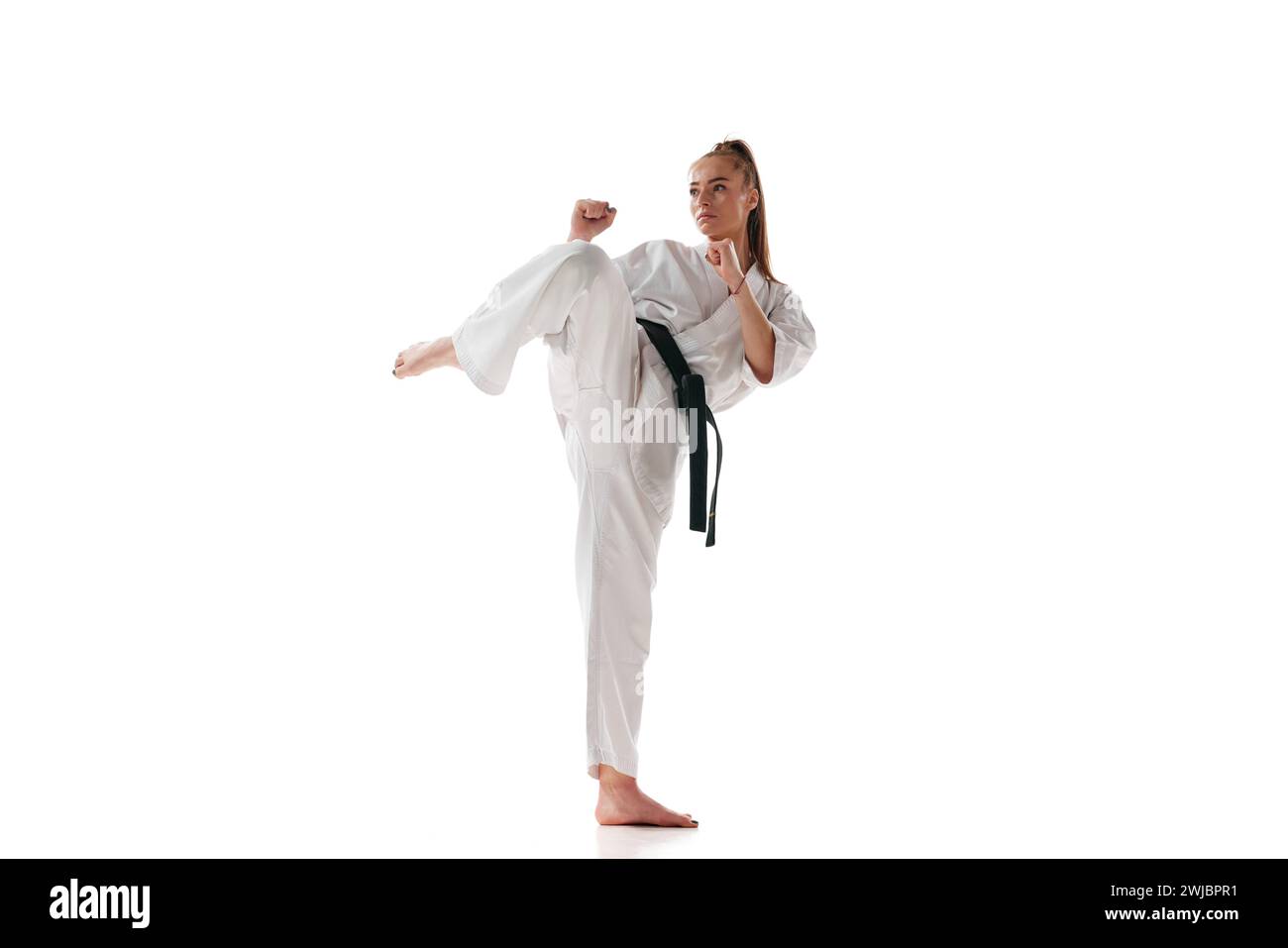 Rear view. Woman professional karate fighter in uniform performing kick ...