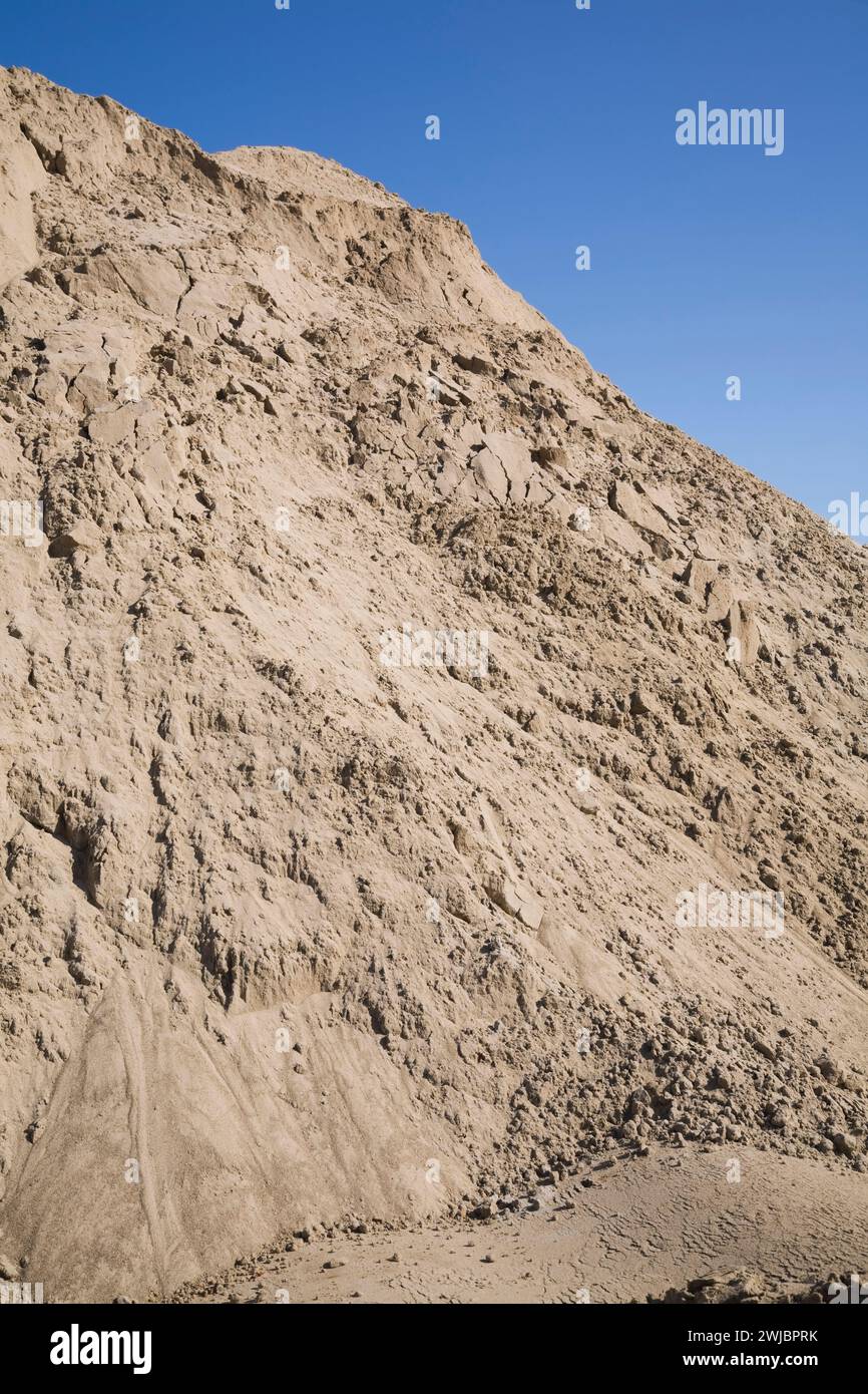 Mound of fine excavated light tan sand against blue sky at construction ...