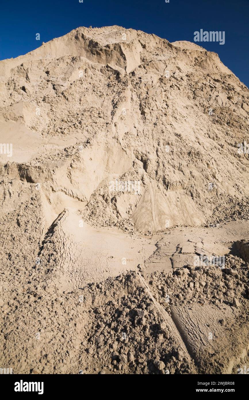 Mound of fine excavated light tan sand against blue sky at construction ...