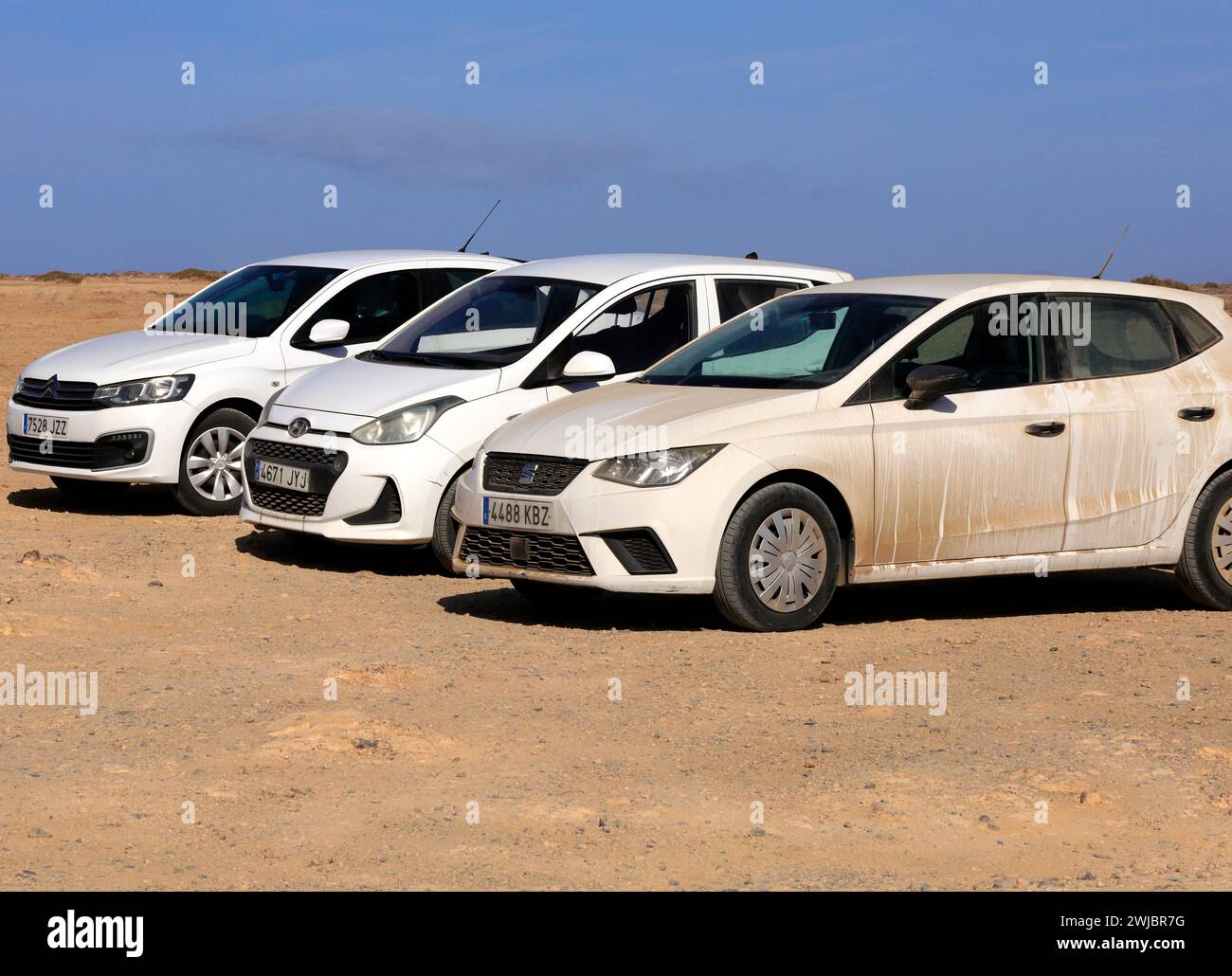 Three white cars parked side by side in a dusty car park, Fuerteventura ...