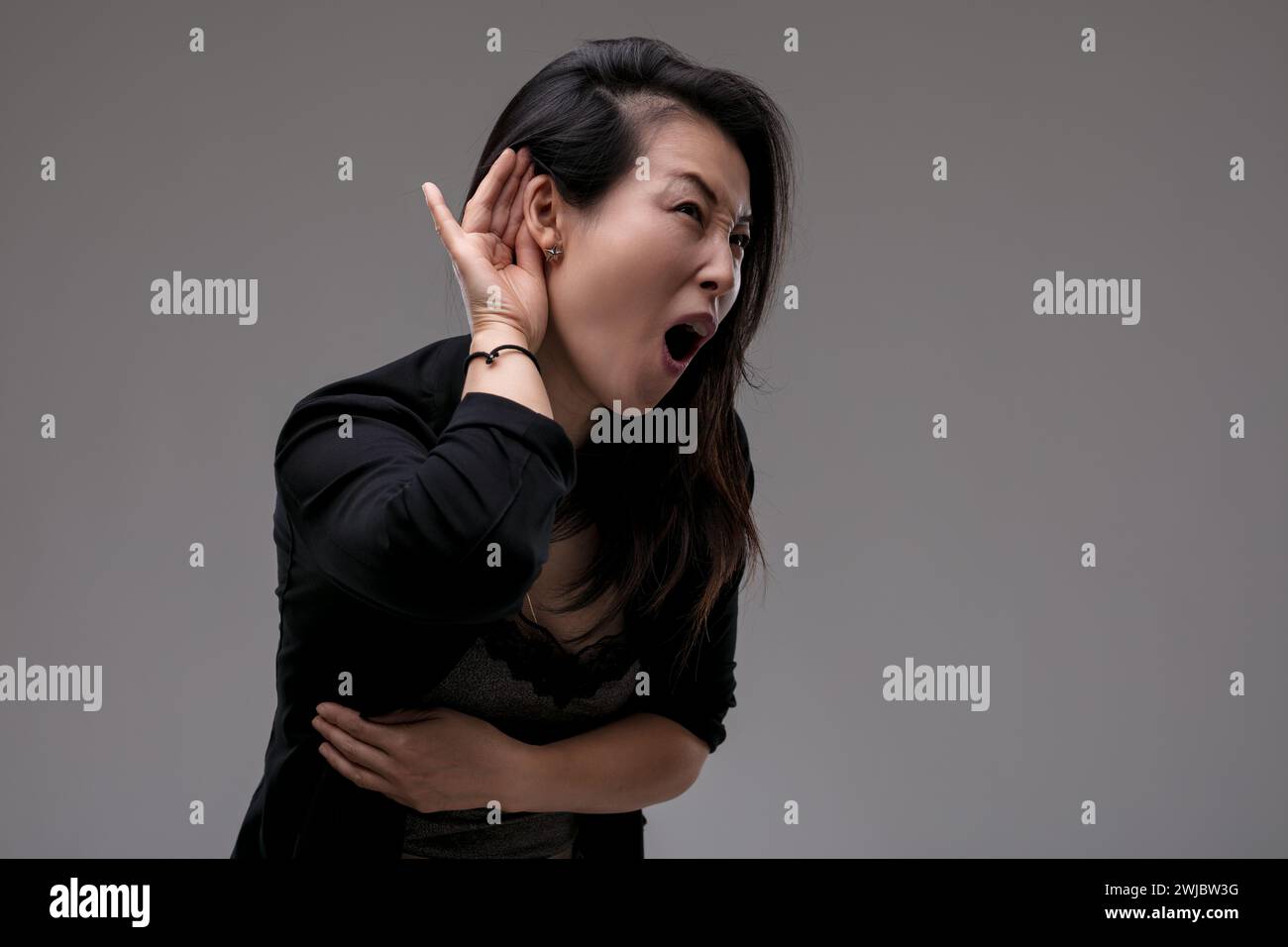 Pained expression and cupped ear, the woman indicates she's hard of ...