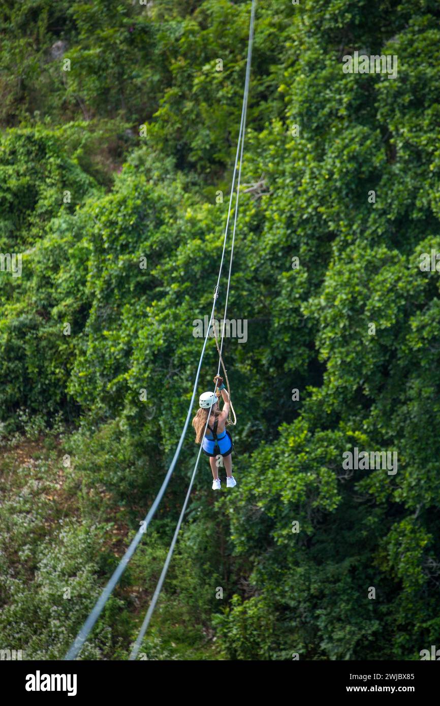 A young woman ziplining over the rainforest near Sosua in the Dominican ...