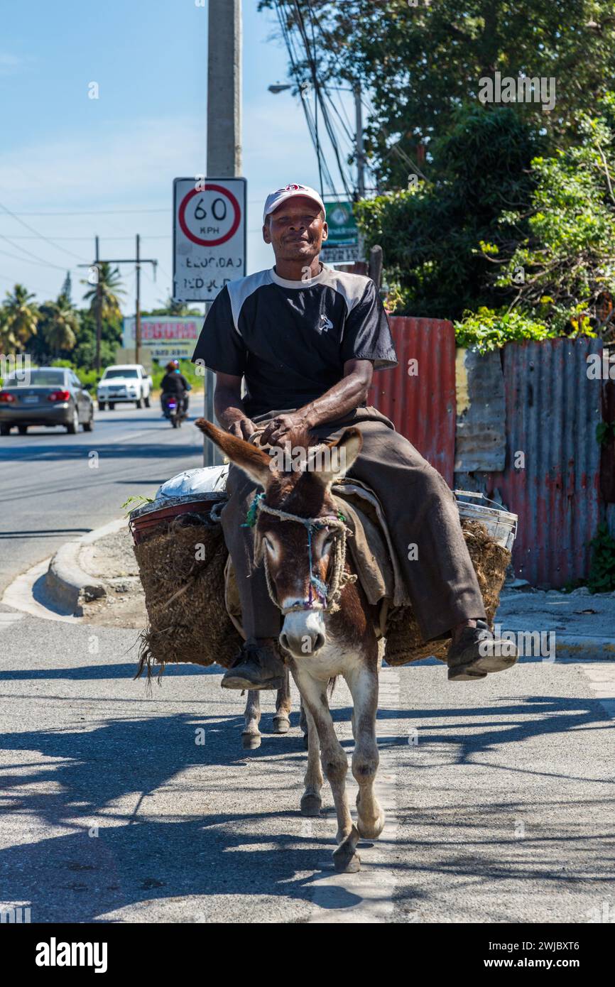 A man rides a burro while leading another loaded burro on the road near ...