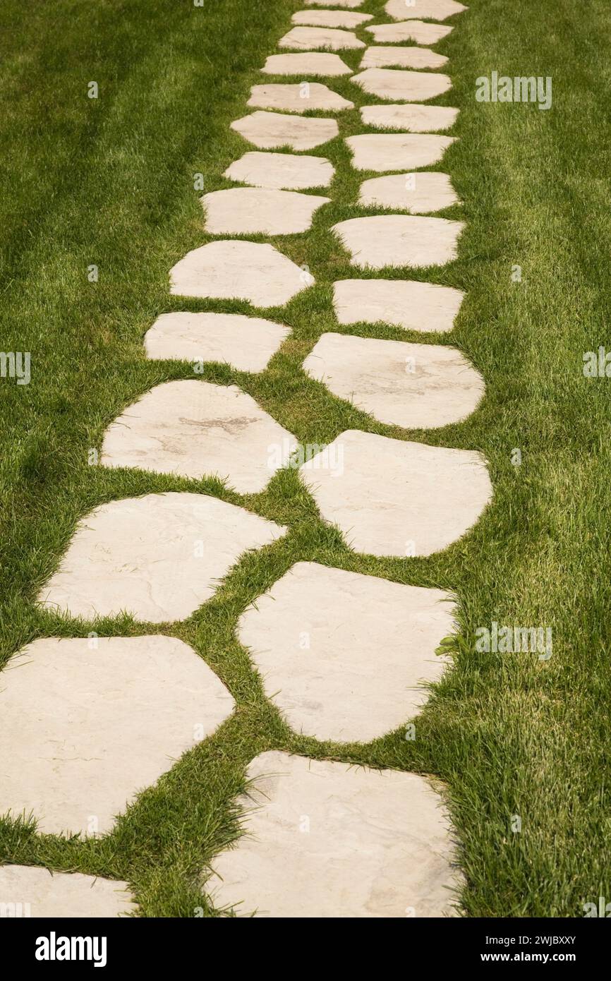 Flagstone walking path laid in grass lawn in backyard in summer Stock ...