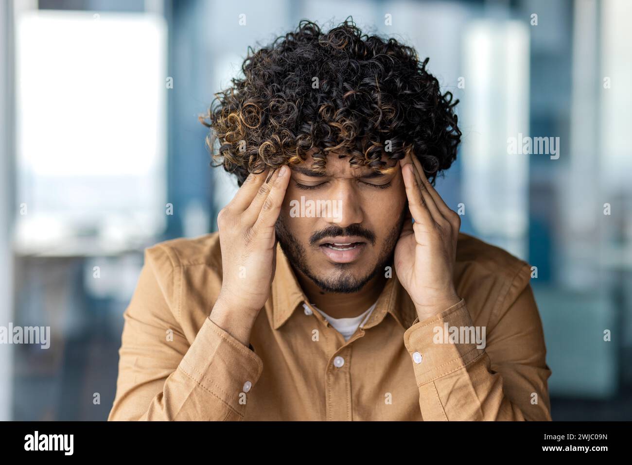 An Indian company employee experiencing stress and headache, working in ...