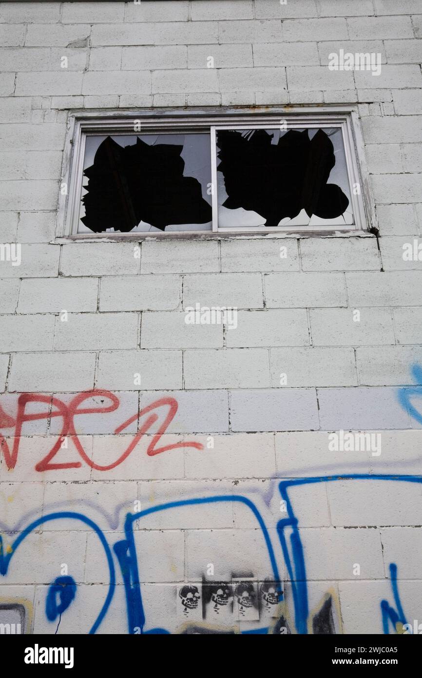 Broken windows and graffiti tags on outside wall of abandoned cement block building Stock Photo ...