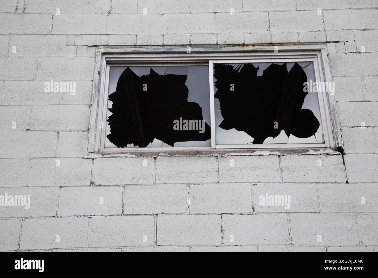 Broken windows on outside wall of abandoned cement block building Stock ...