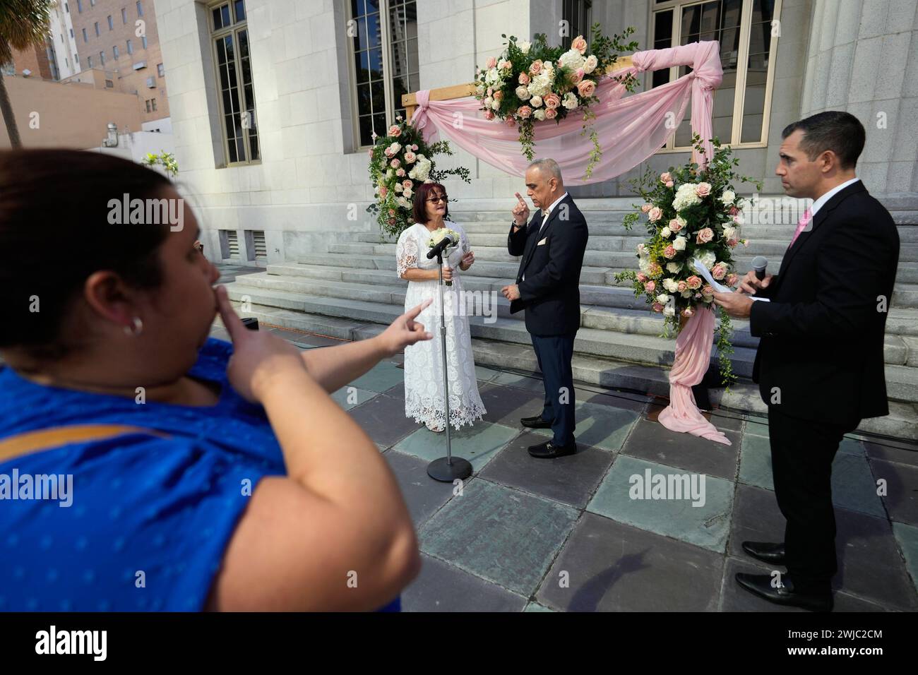 Rene Cruz Prado, center right, uses American Sign Language to say "I do ...