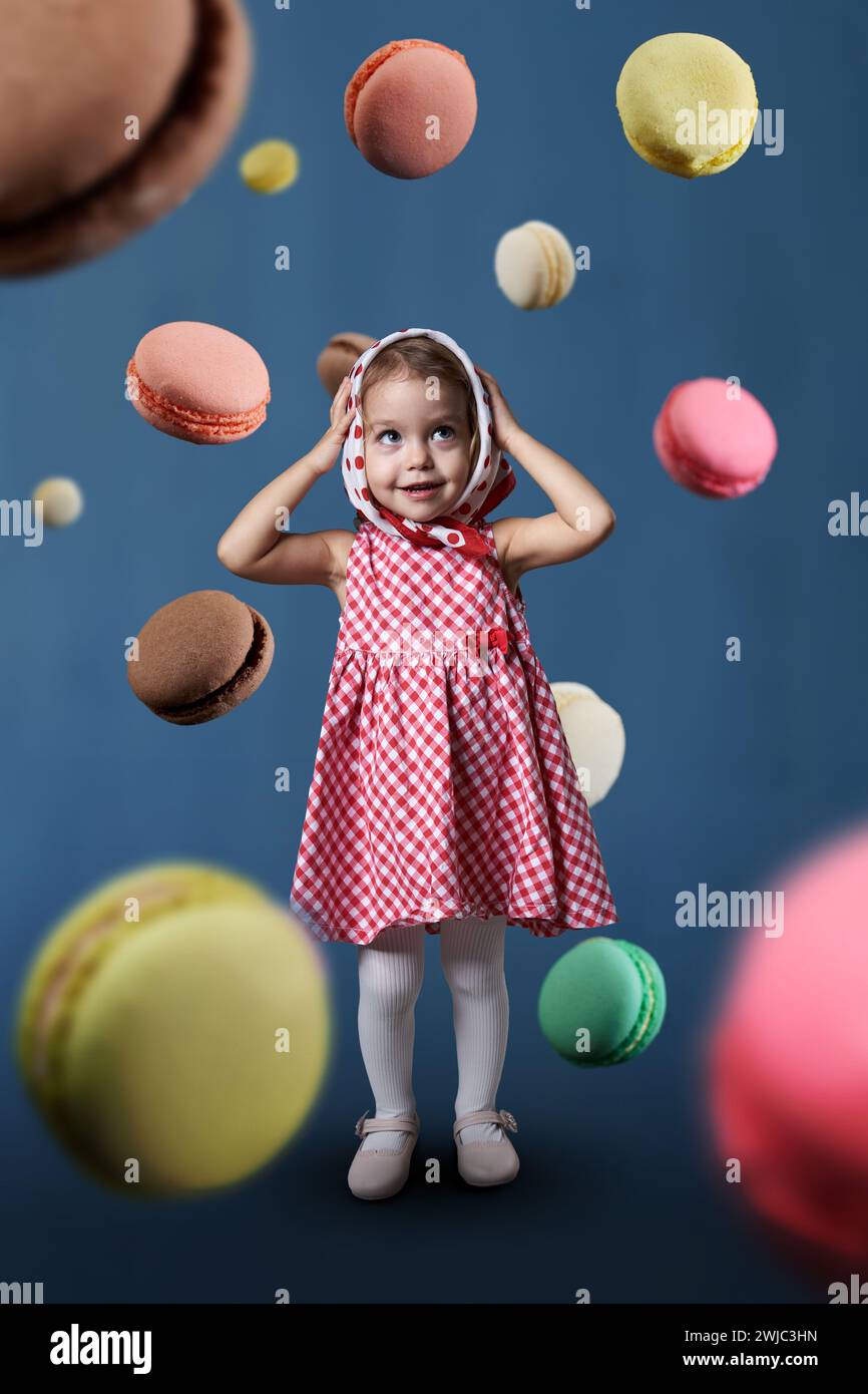 Happy little girl surrounded by a rain of flying macarons, conceptual ...