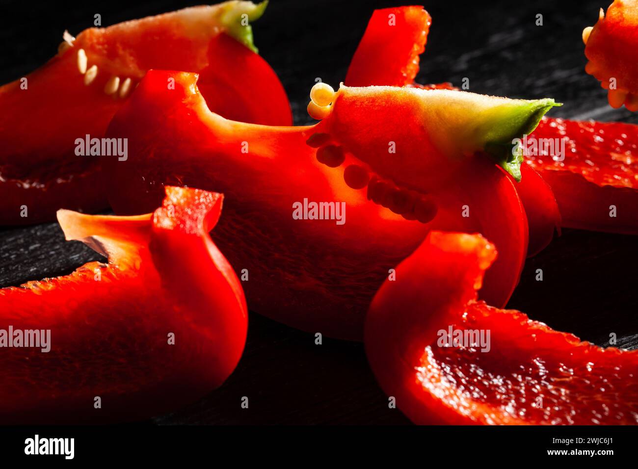 sliced red bell pepper on black wood background Stock Photo - Alamy