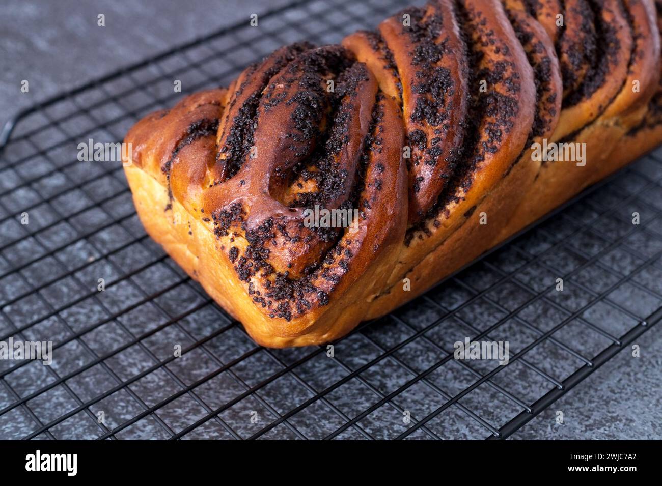 A whole bun with poppy seed filling lies on a hot stand, black ...