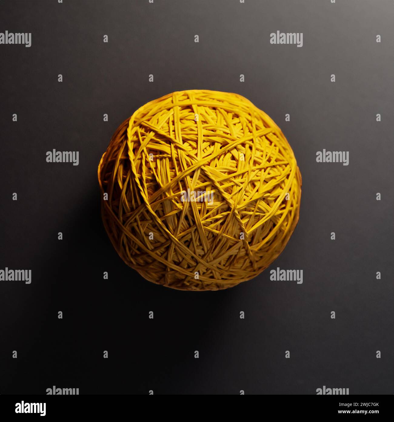 Bright yellow ball made of office rubber bands, showcased against a ...