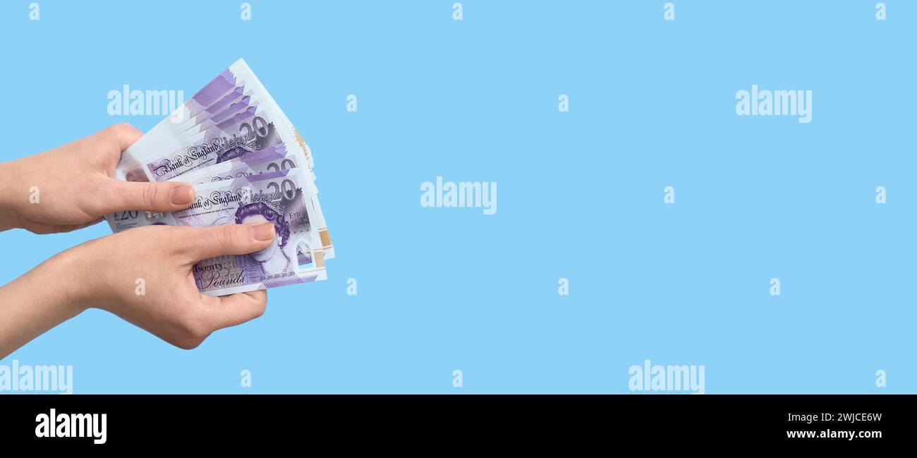 Female hands holding pound sterling banknotes on light blue background ...