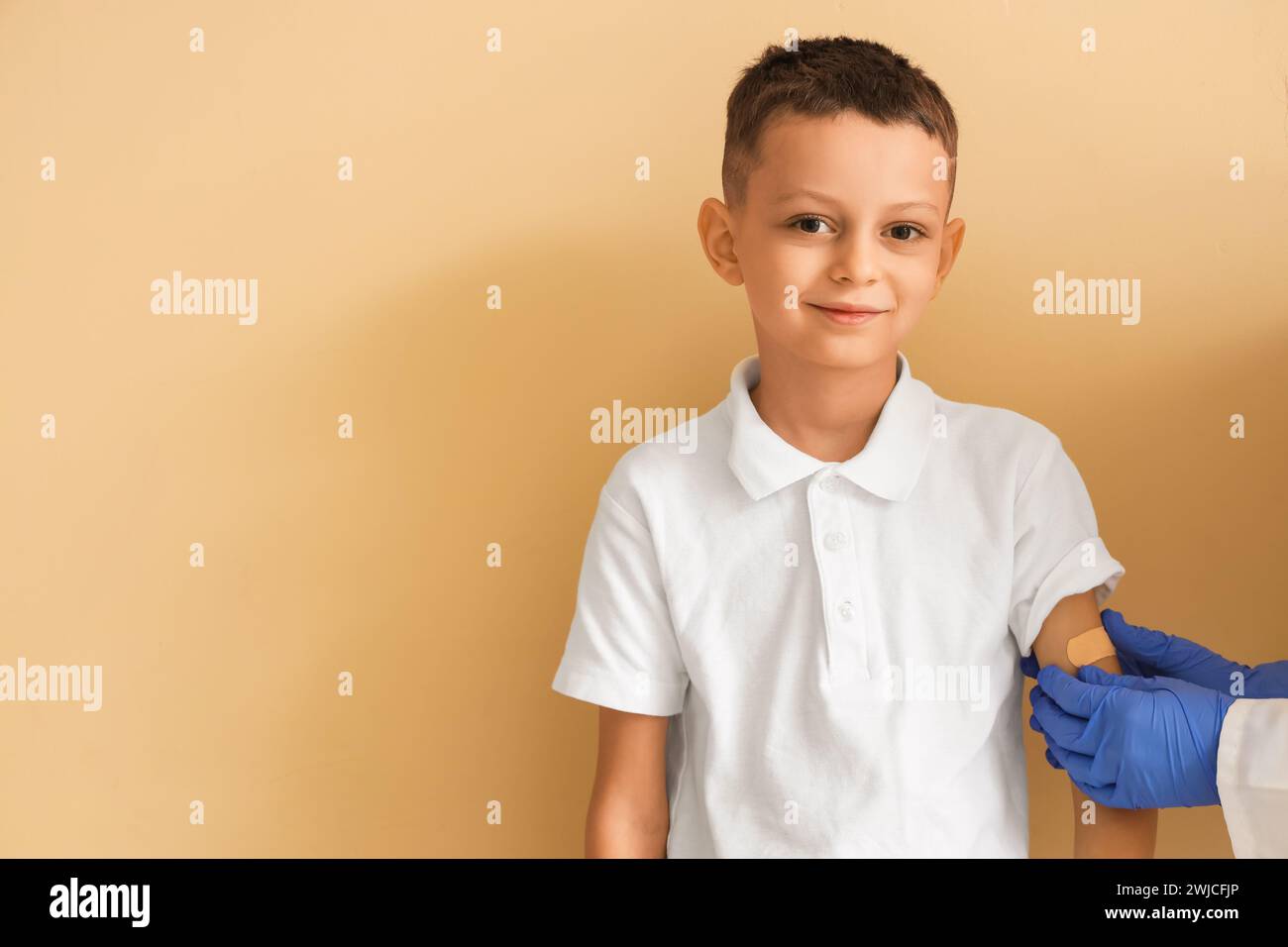 Little boy receiving plaster from doctor after vaccination on beige ...