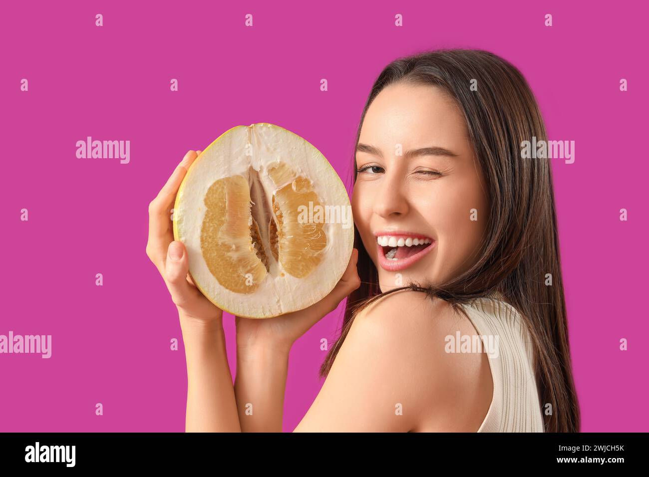 Smiling young woman with half of pomelo on purple background, closeup ...