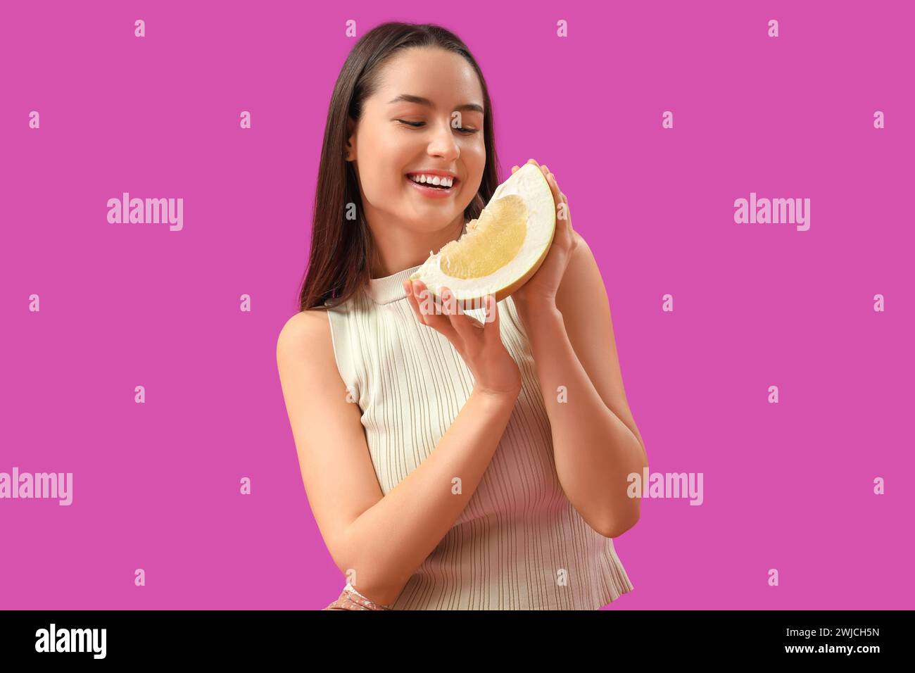Smiling young woman with pomelo slice on purple background Stock Photo ...