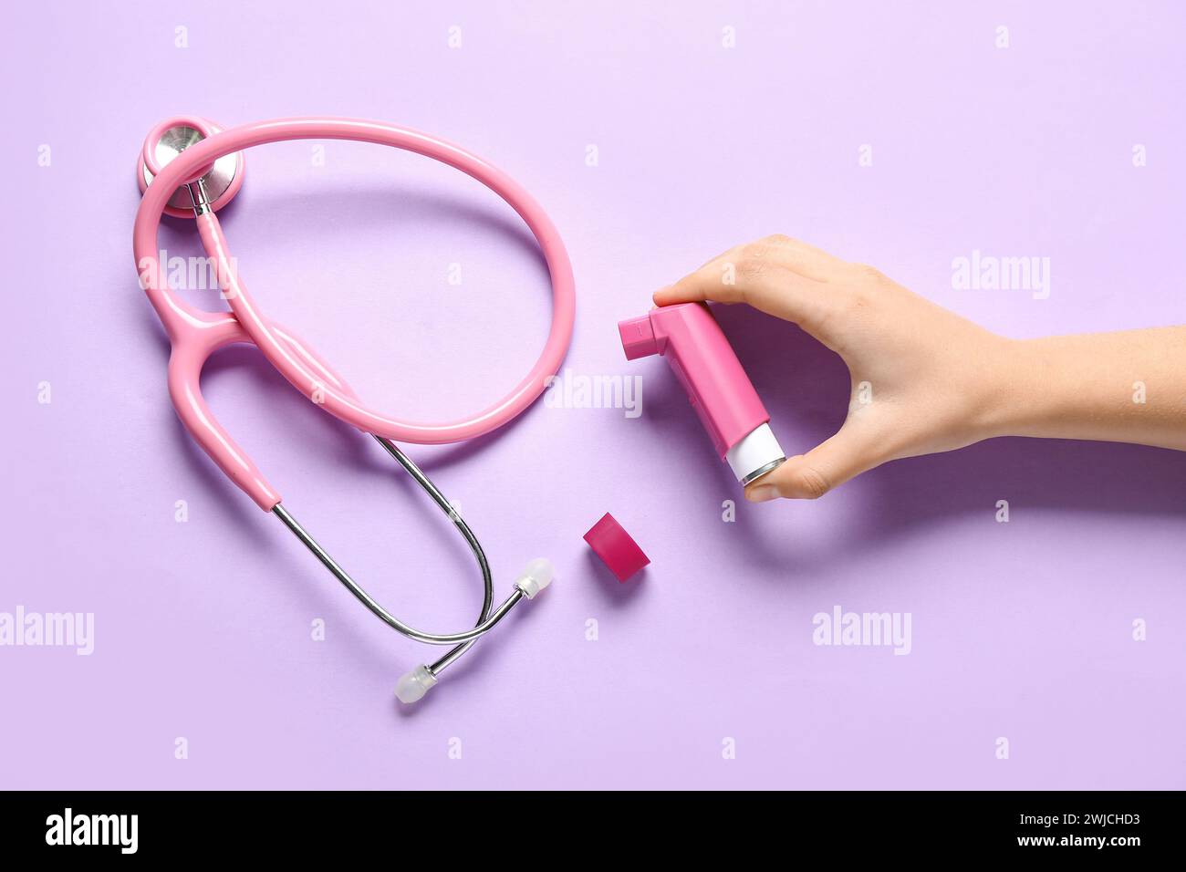 Child's hand with asthma inhaler and stethoscope on lilac background ...