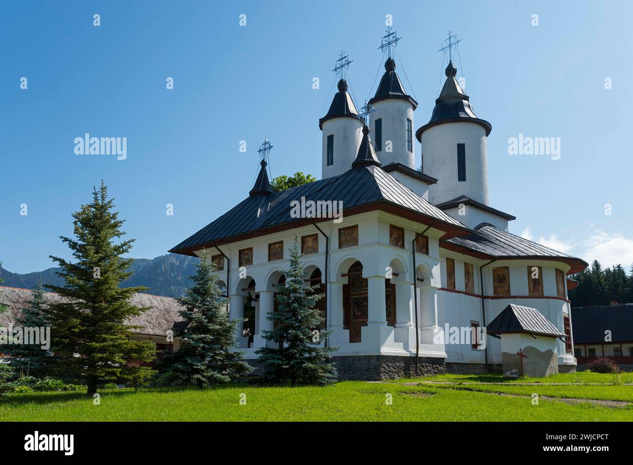 White orthodox church building with black roofs under a clear blue sky ...