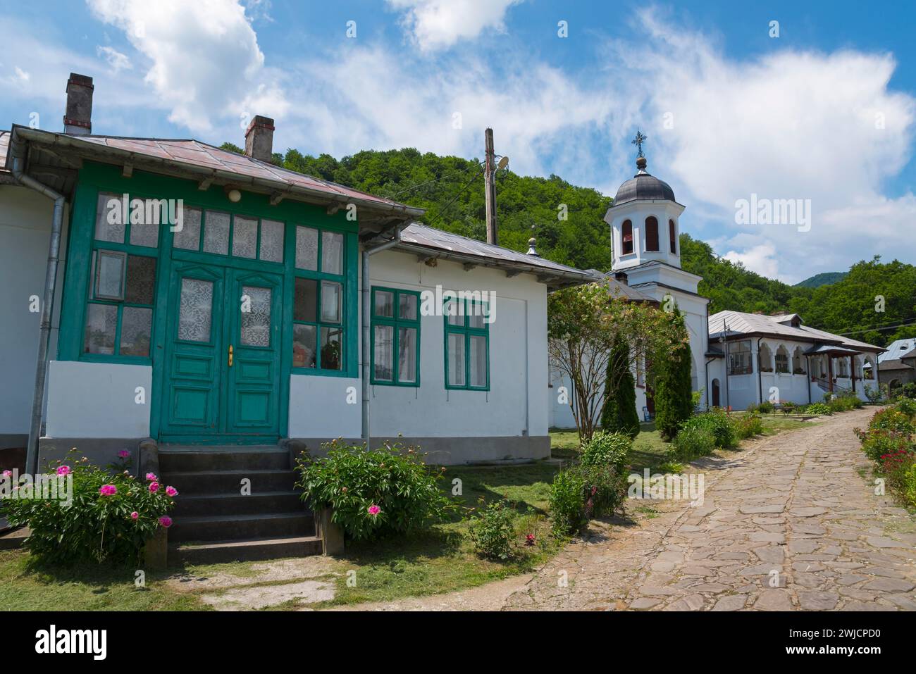 Traditional monastery building with green shutters and flowers along a ...