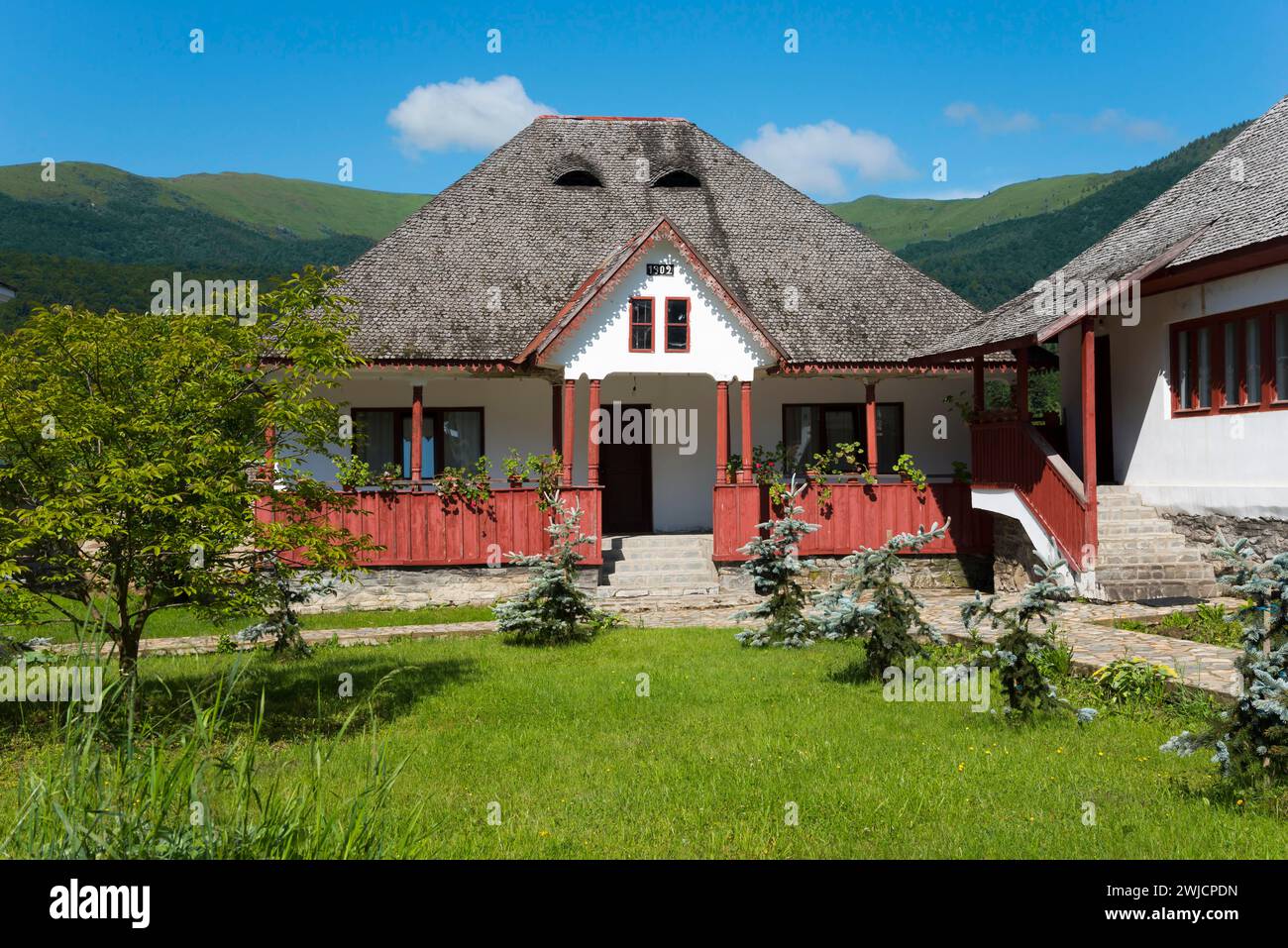 Traditional house with shingle roof and red fence in front of ...