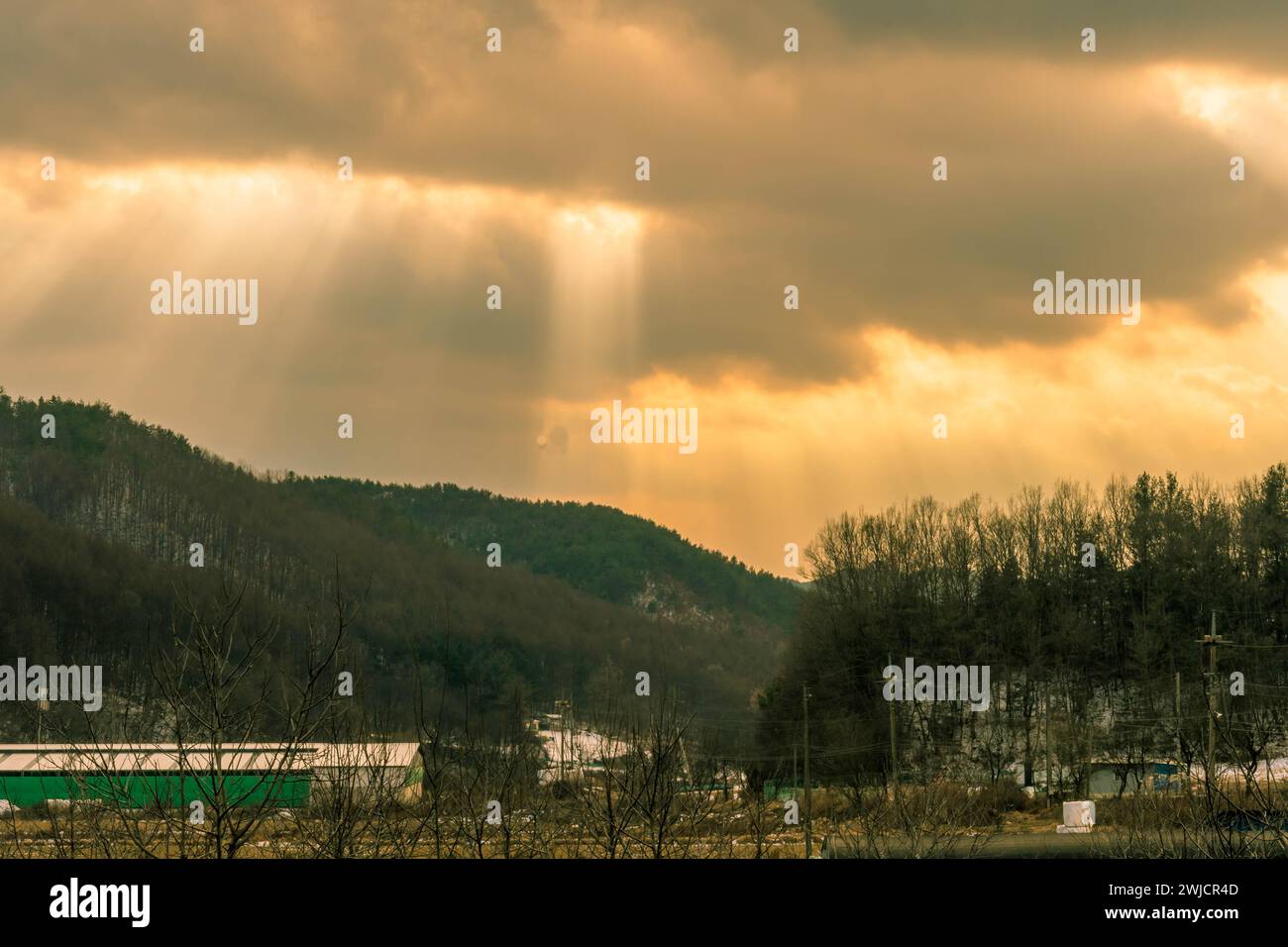 Sun rays break through dark clouds sending beans of light to wintery ...