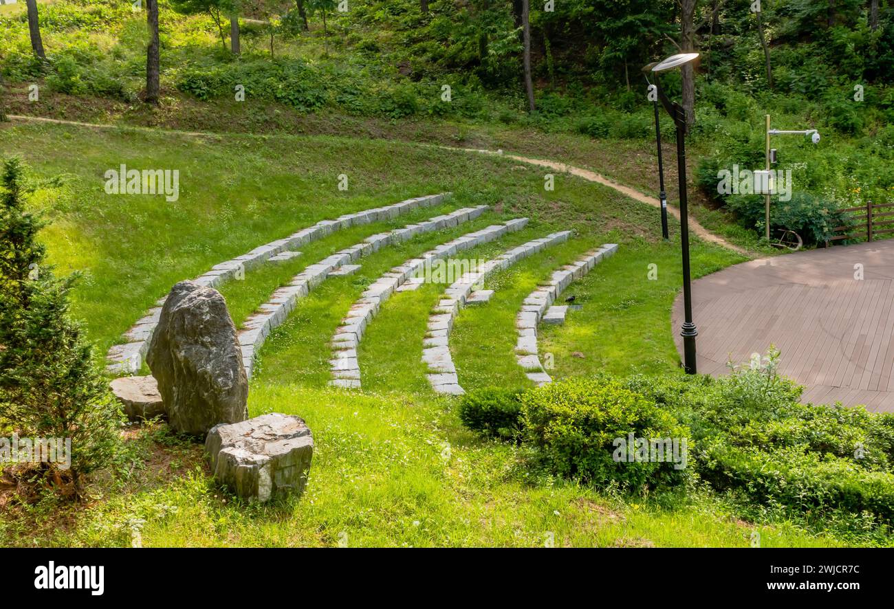 Amphitheater seating in public park made of concrete blocks with trees ...